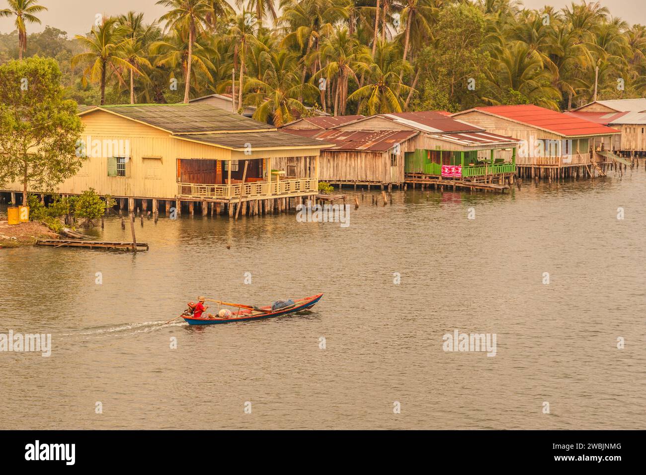 long tail boat passes riverside houses during the dry season, Southern ...