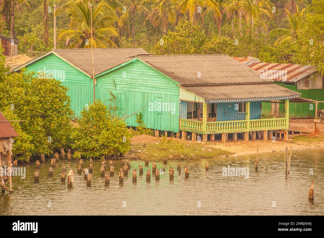 colorful turquoise house on the bank of a river during the dry season ...