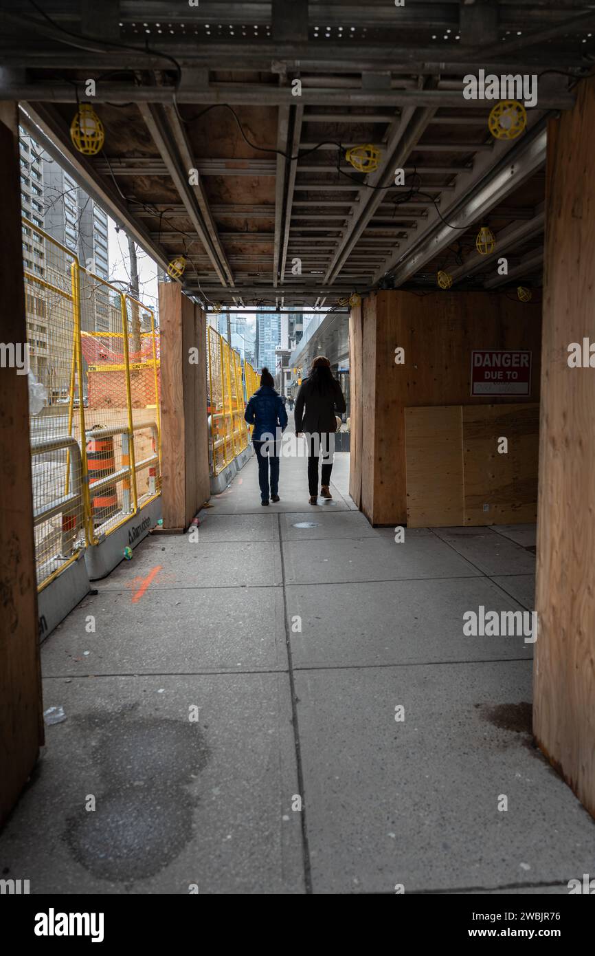 The two people walk under a construction structure in downtown Toronto ...