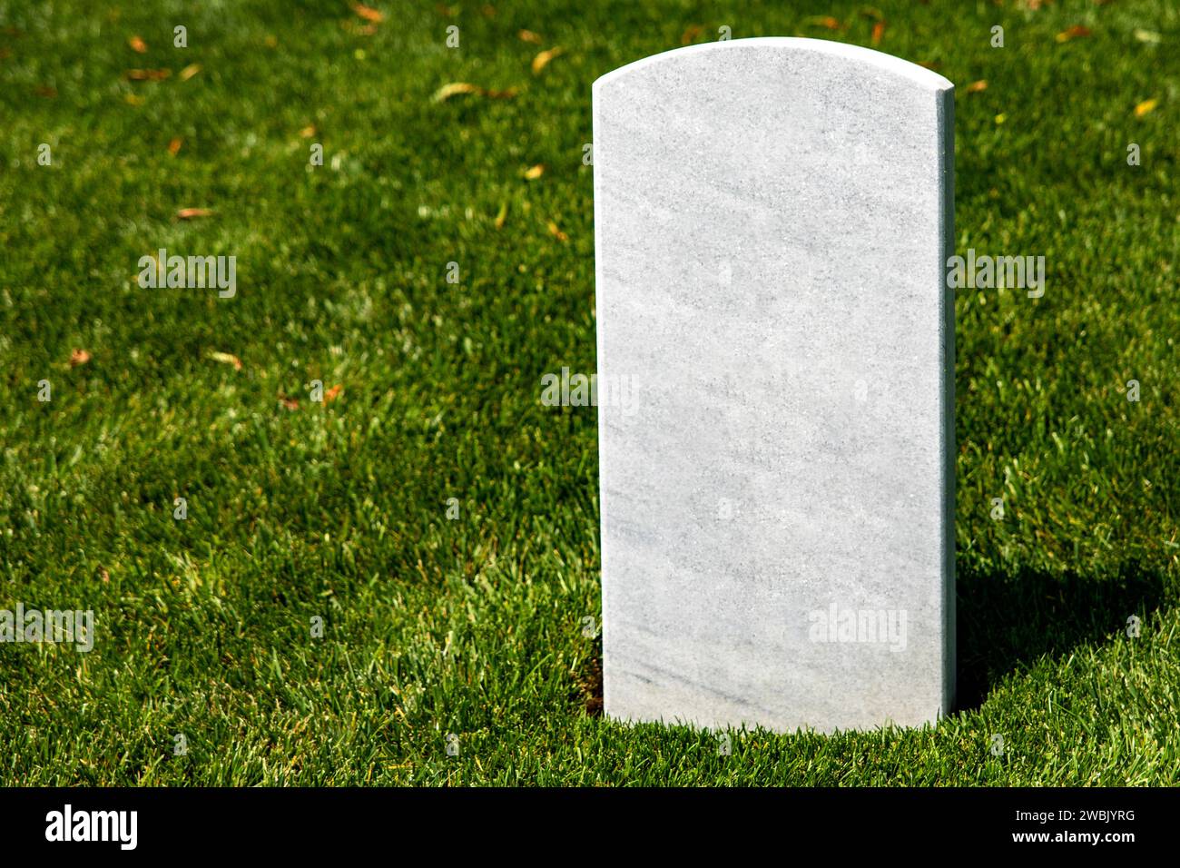 A white marble tombstone on a grassy lawn at Arlington National ...