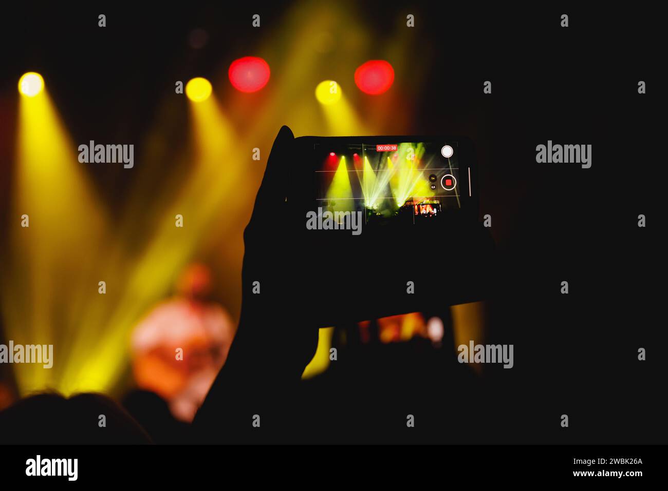 Bright stage lights illuminate a concert. Yellow glow radiates from ...