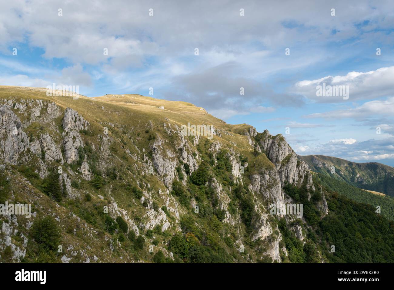 Mountain overgrown in grass with rocky cliffs and slopes covered with ...