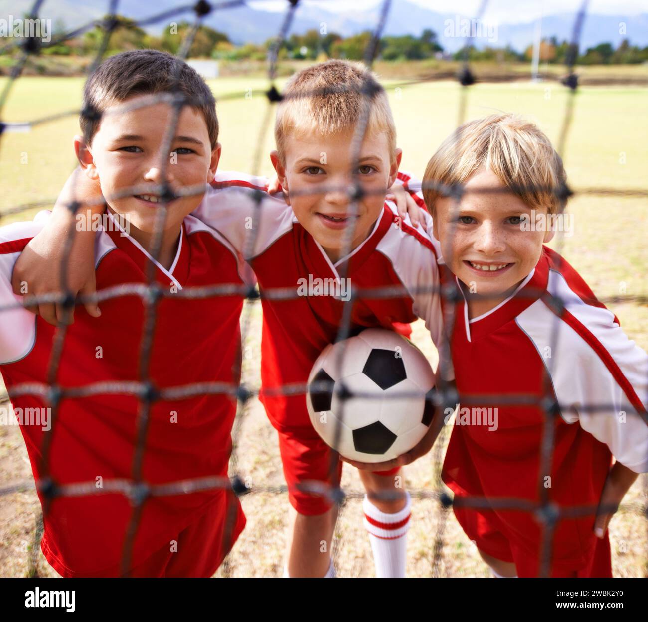 Kids, soccer team and portrait with smile, goal net and boys with ...