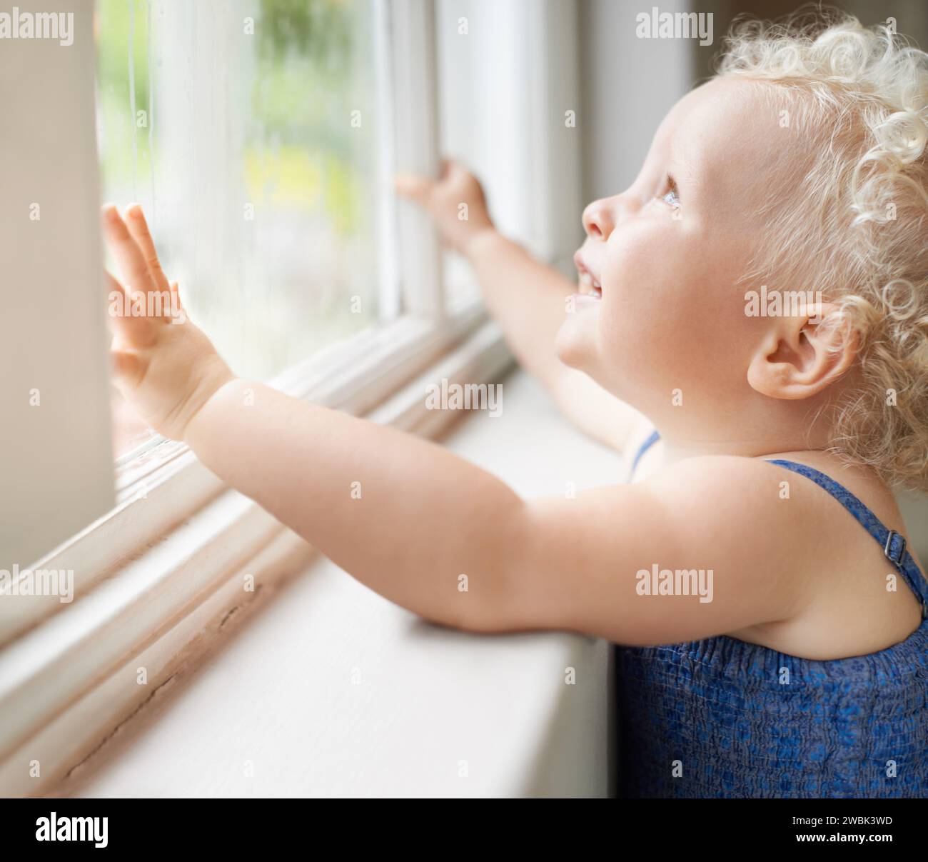Happy, window and toddler with smile standing against glass or wall in ...