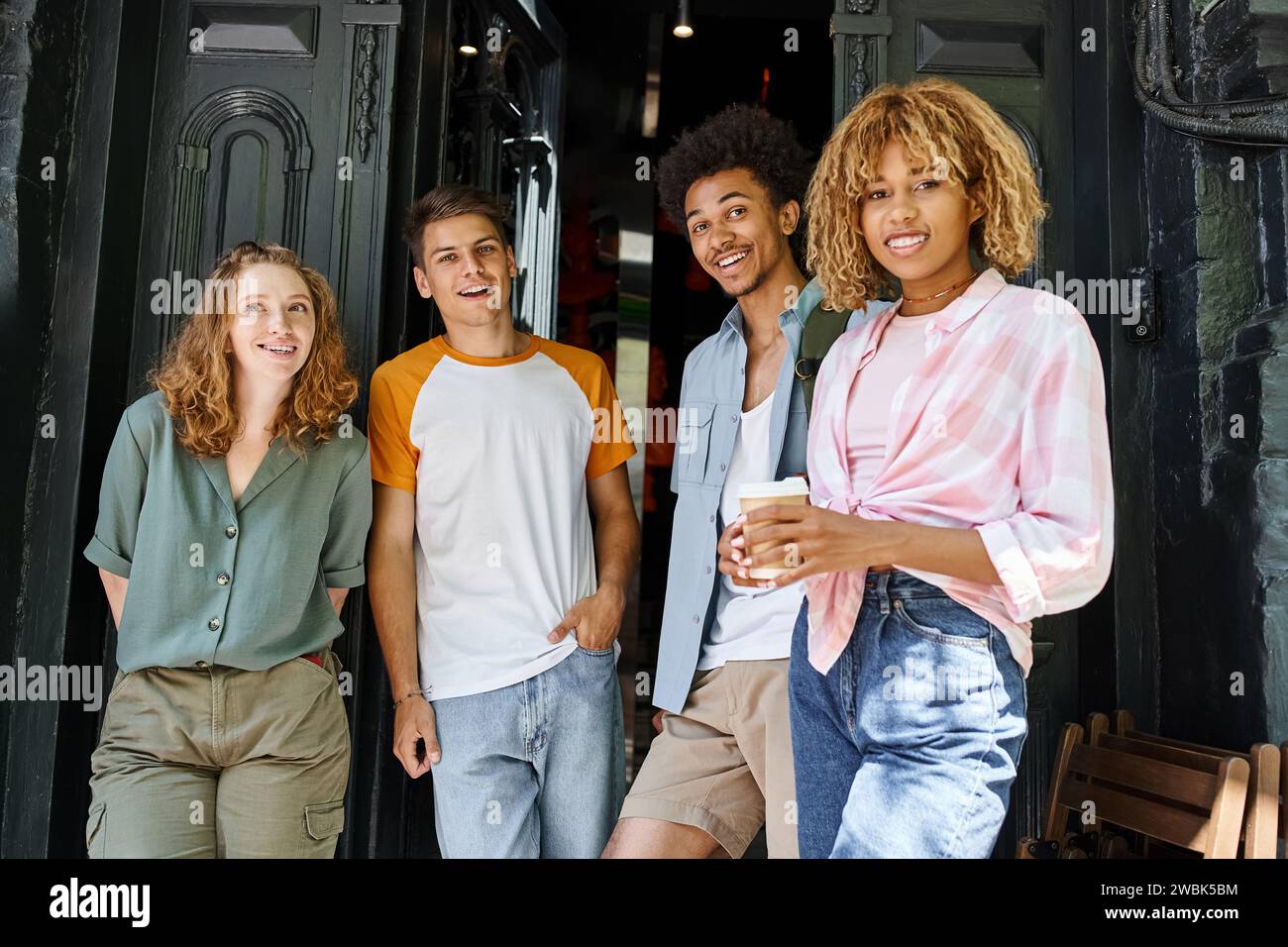 happy and trendy multiethnic students looking at camera near hostel on ...