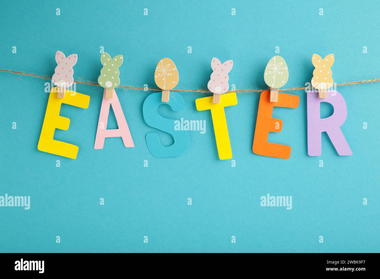 Inscription Easter on blue background, a rope with clothespins. The ...
