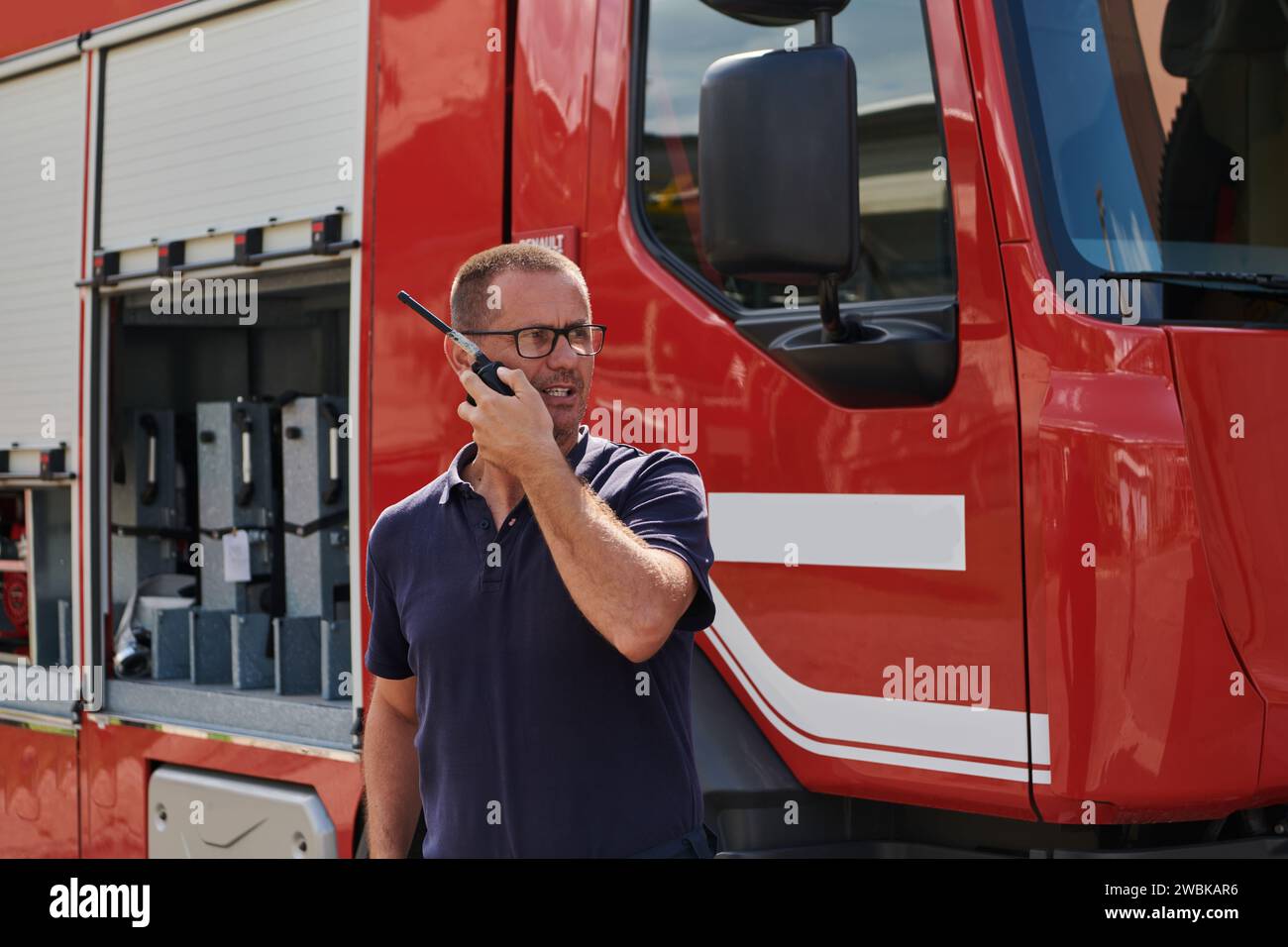 A dedicated firefighter, captured in a moment of communication, stands ...