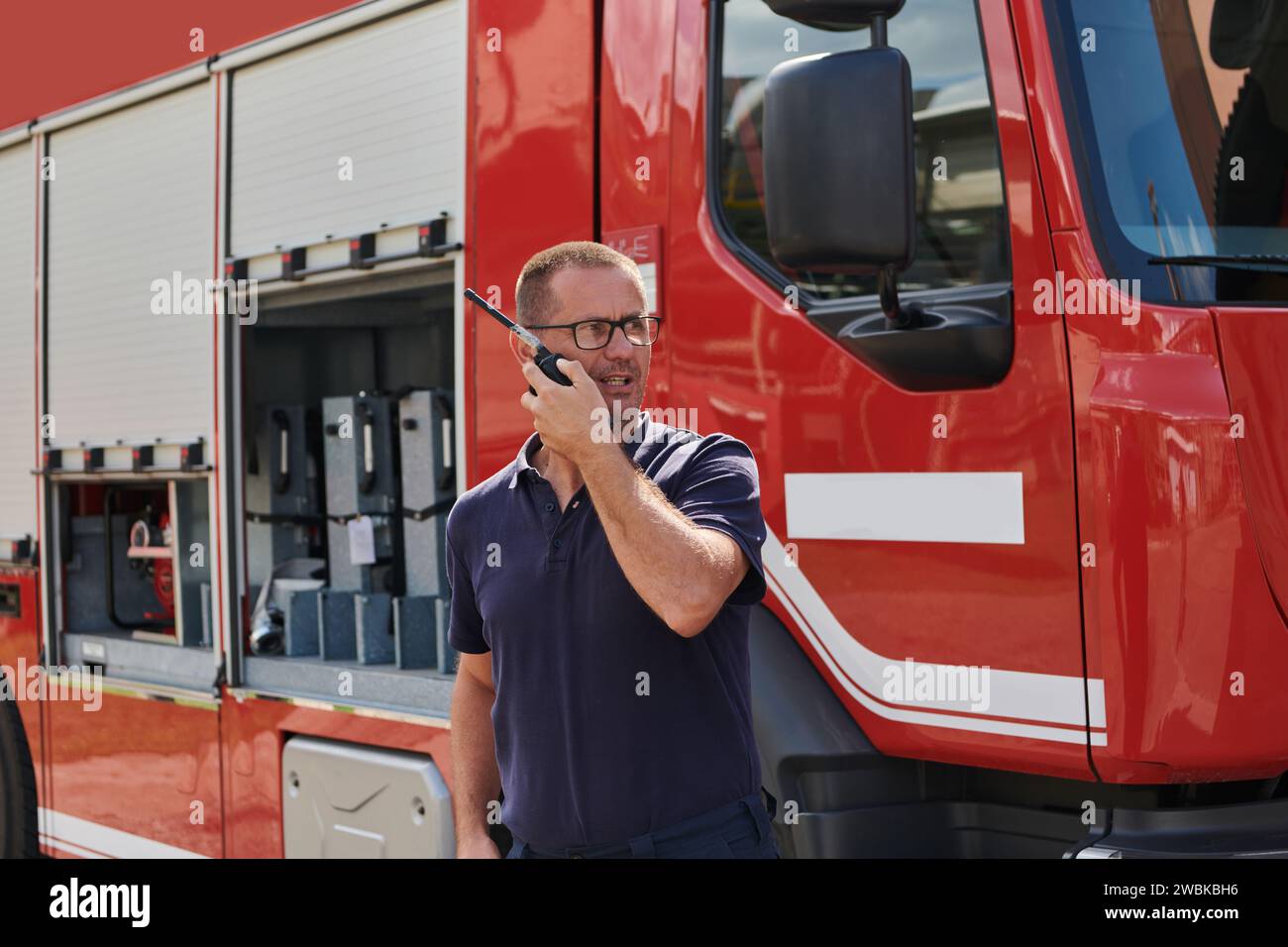 A dedicated firefighter, captured in a moment of communication, stands ...