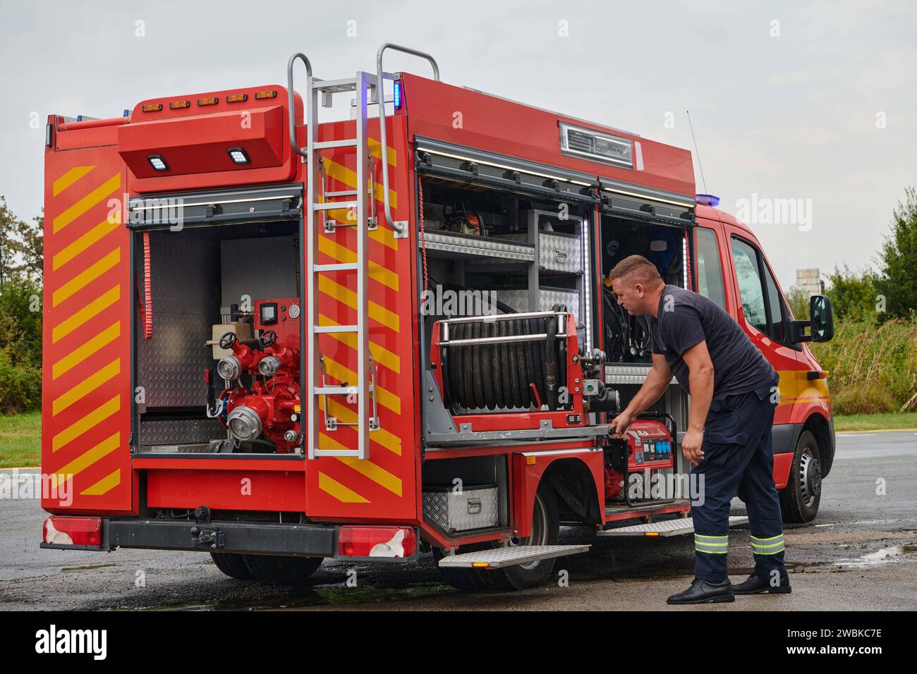 A dedicated firefighter preparing a modern firetruck for deployment to ...