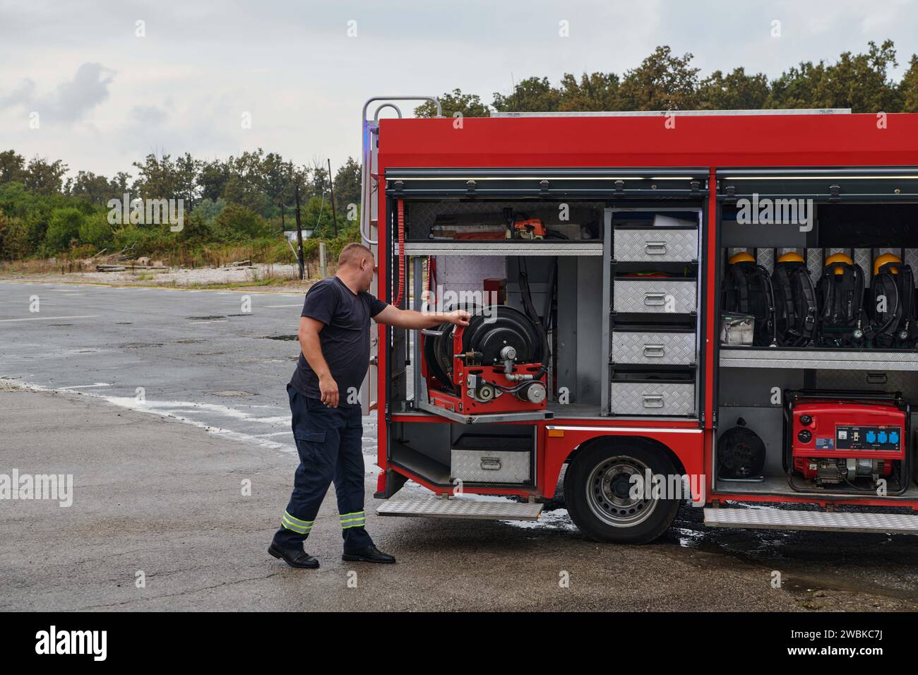 A dedicated firefighter preparing a modern firetruck for deployment to ...