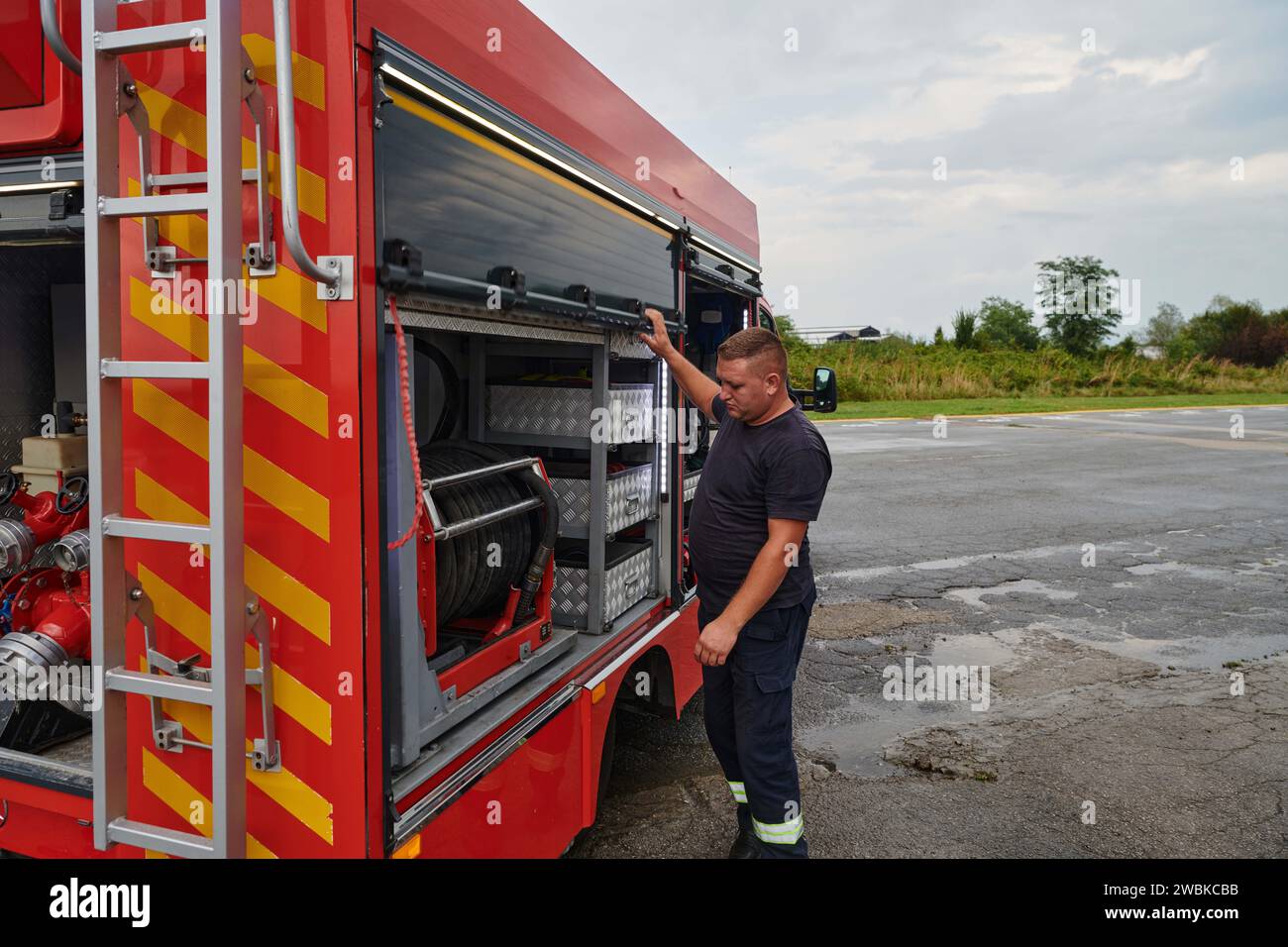 A dedicated firefighter preparing a modern firetruck for deployment to ...