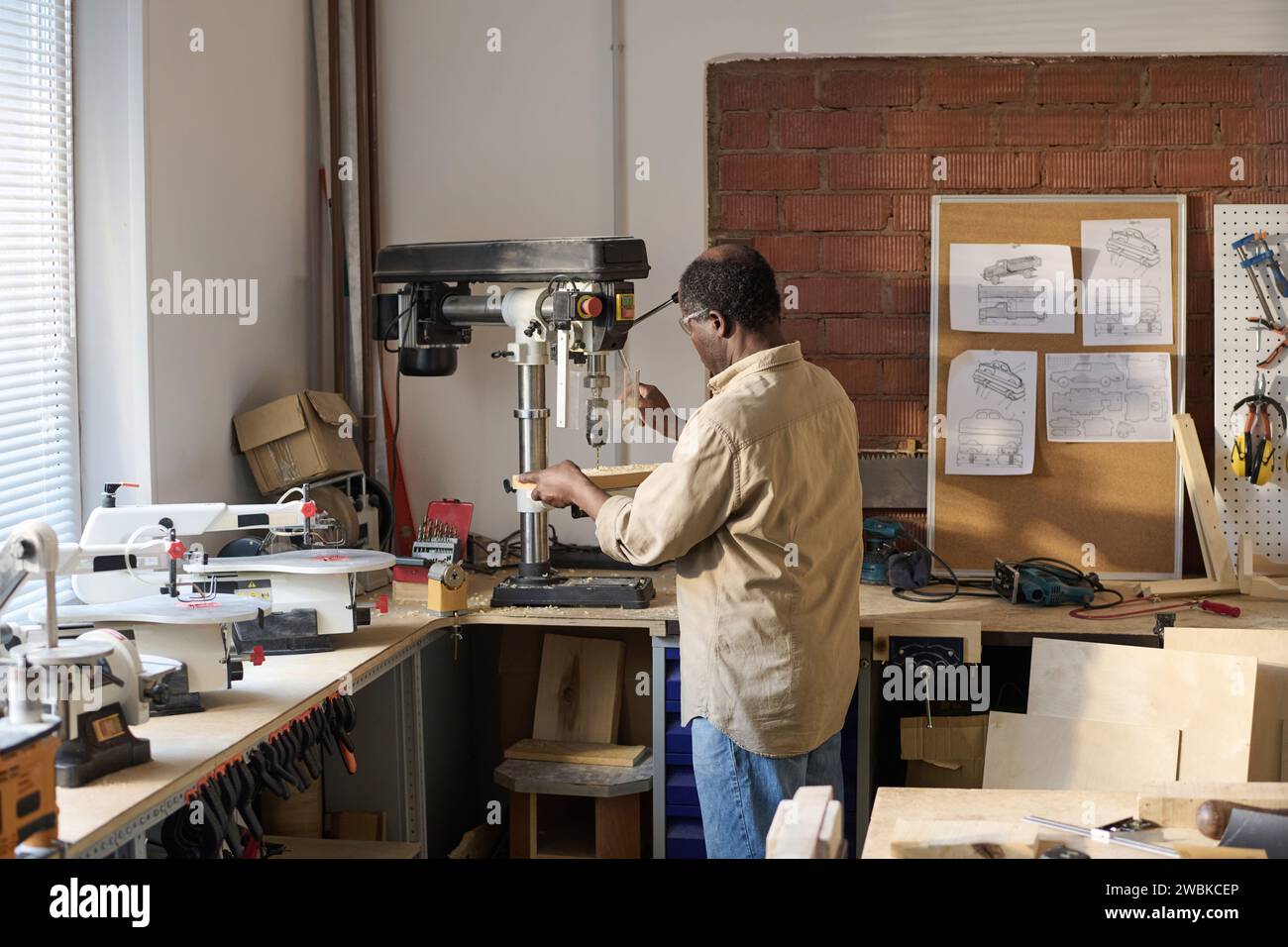 Back view of senior African American man cutting wood using machines in ...