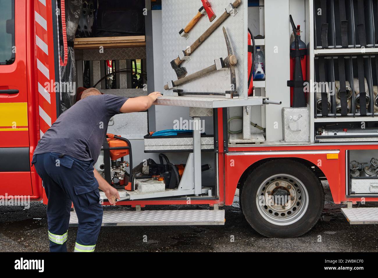 A dedicated firefighter preparing a modern firetruck for deployment to ...