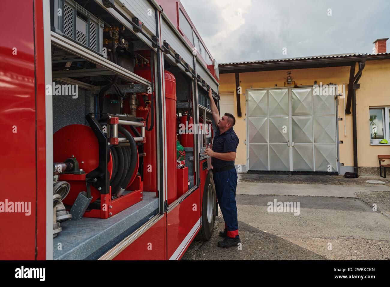 A dedicated firefighter preparing a modern firetruck for deployment to ...