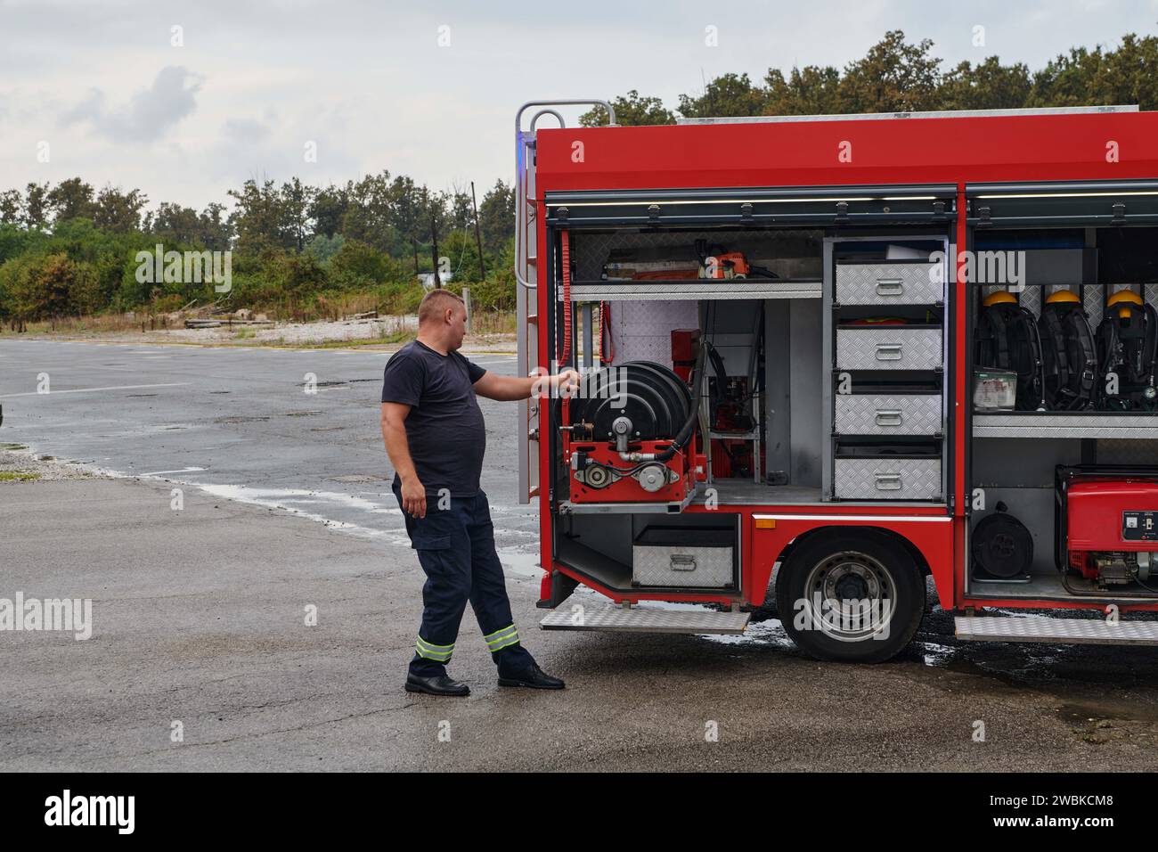 A dedicated firefighter preparing a modern firetruck for deployment to ...
