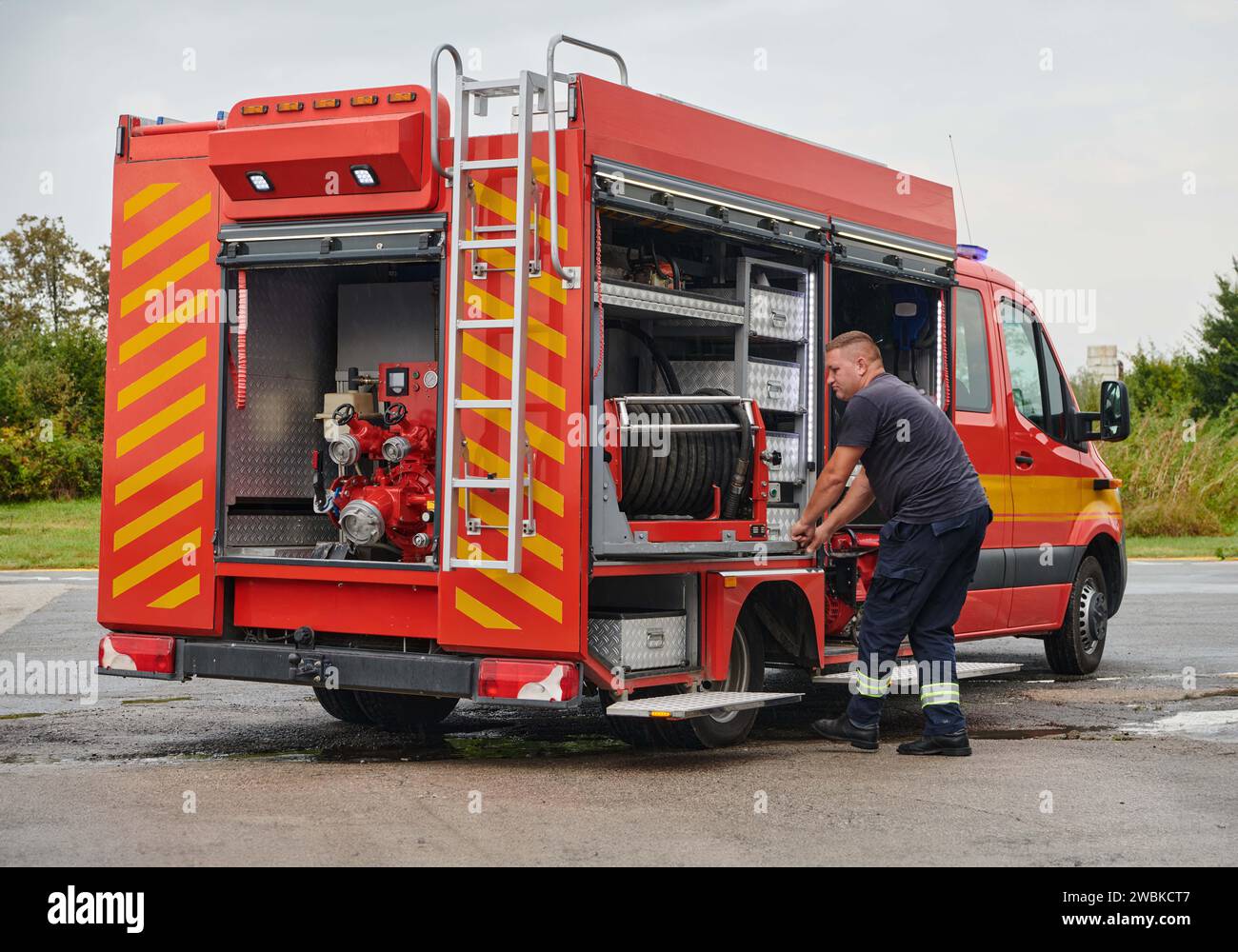 A dedicated firefighter preparing a modern firetruck for deployment to ...