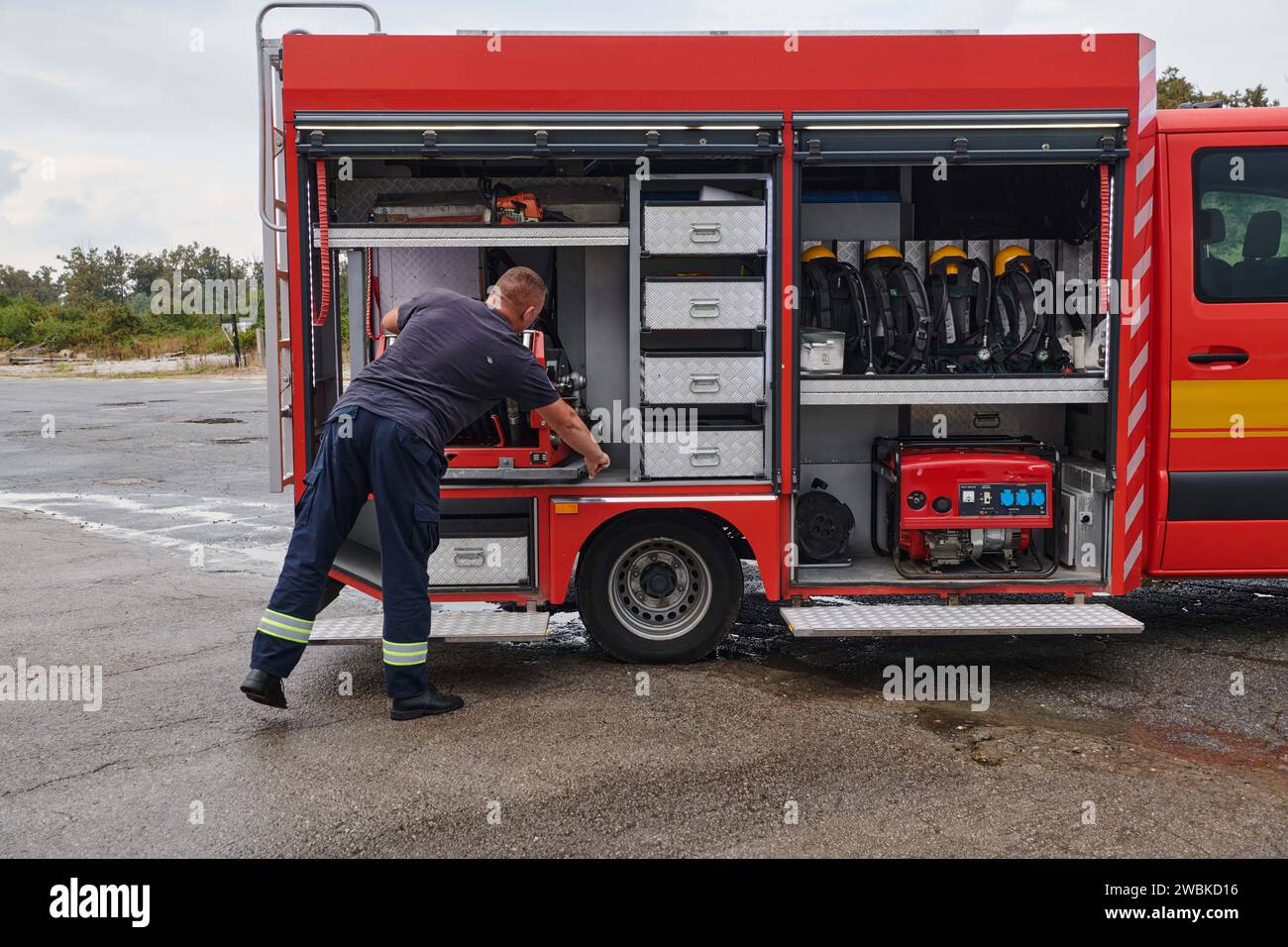 A dedicated firefighter preparing a modern firetruck for deployment to ...