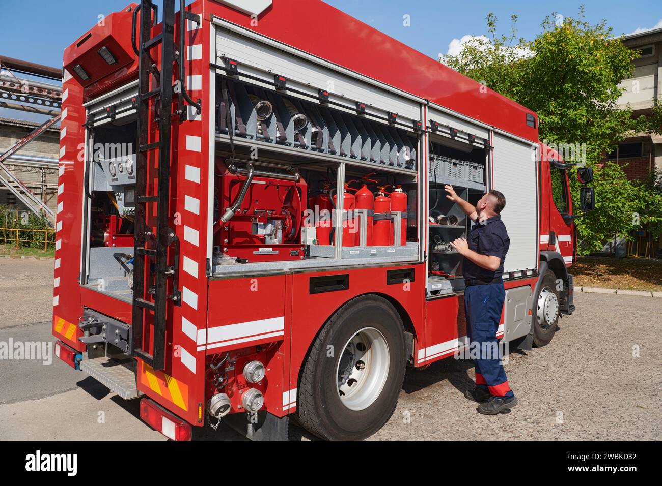 A dedicated firefighter preparing a modern firetruck for deployment to ...