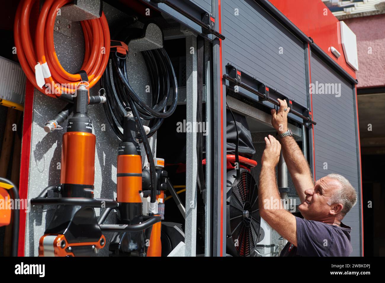 A dedicated firefighter preparing a modern firetruck for deployment to ...