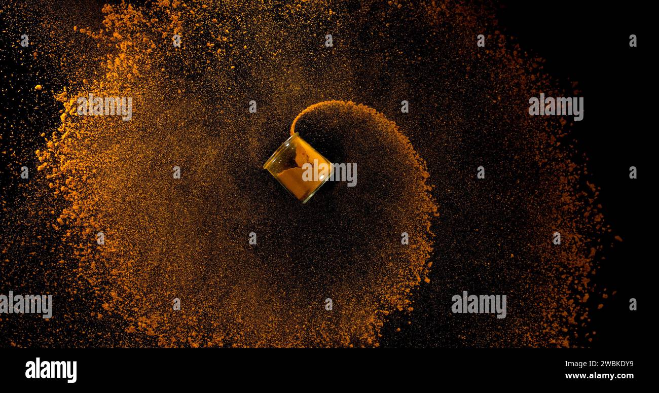 Curry Powder into a Small Jar falling against Black Background Stock ...
