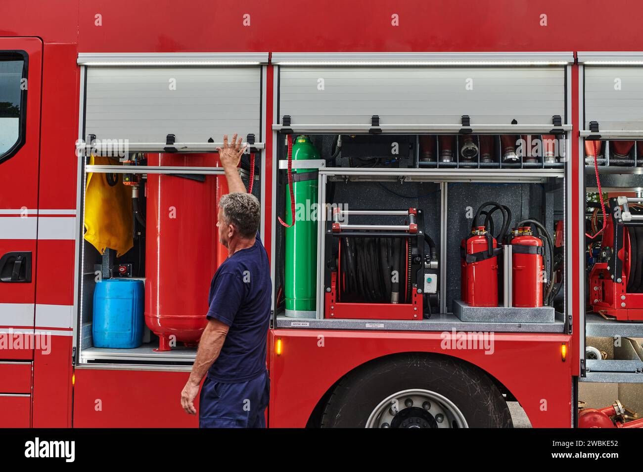 A dedicated firefighter preparing a modern firetruck for deployment to ...