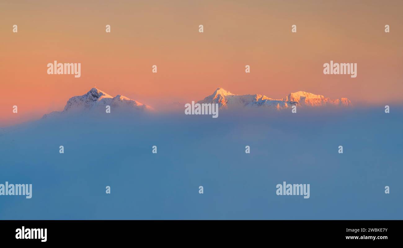 Snow-covered mountains in the last sunlight rising out of the cloud ...