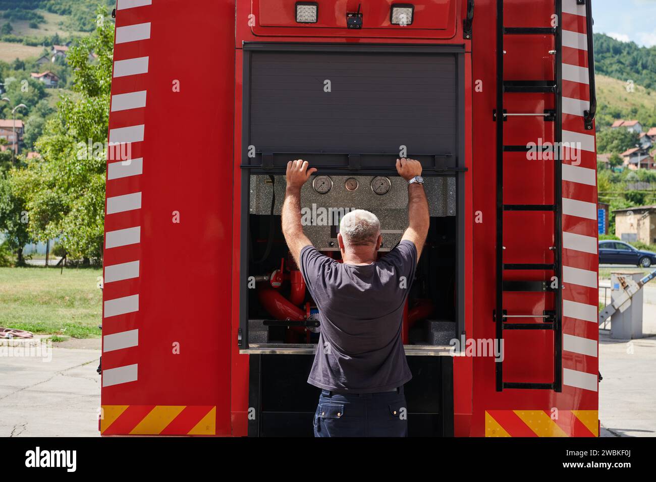 A dedicated firefighter preparing a modern firetruck for deployment to ...
