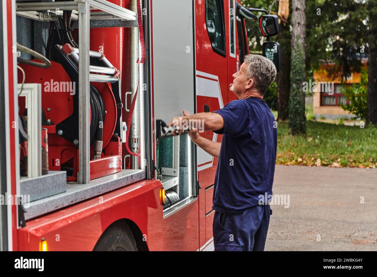 A dedicated firefighter preparing a modern firetruck for deployment to ...