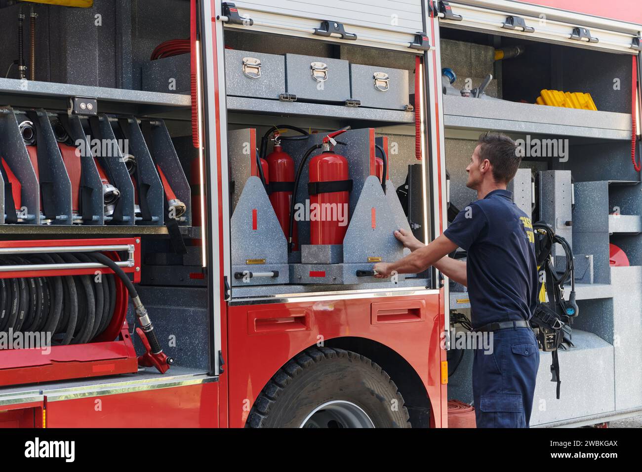A dedicated firefighter preparing a modern firetruck for deployment to ...
