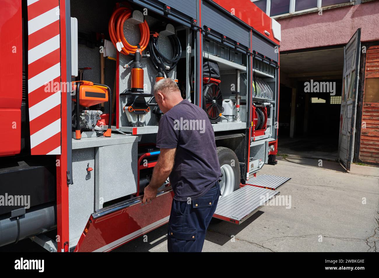 A dedicated firefighter preparing a modern firetruck for deployment to ...