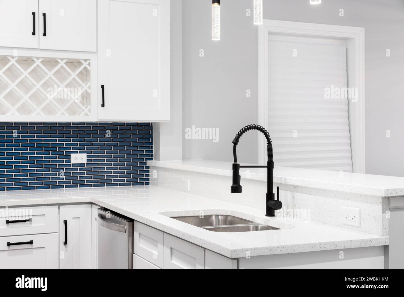 A kitchen detail with a black faucet, glass light fixtures hanging ...