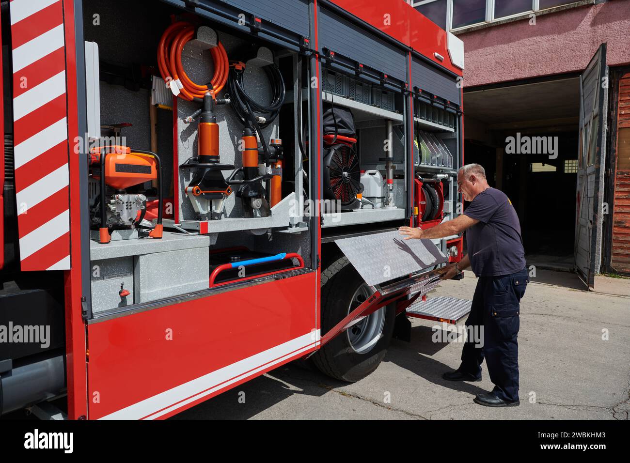 A dedicated firefighter preparing a modern firetruck for deployment to ...