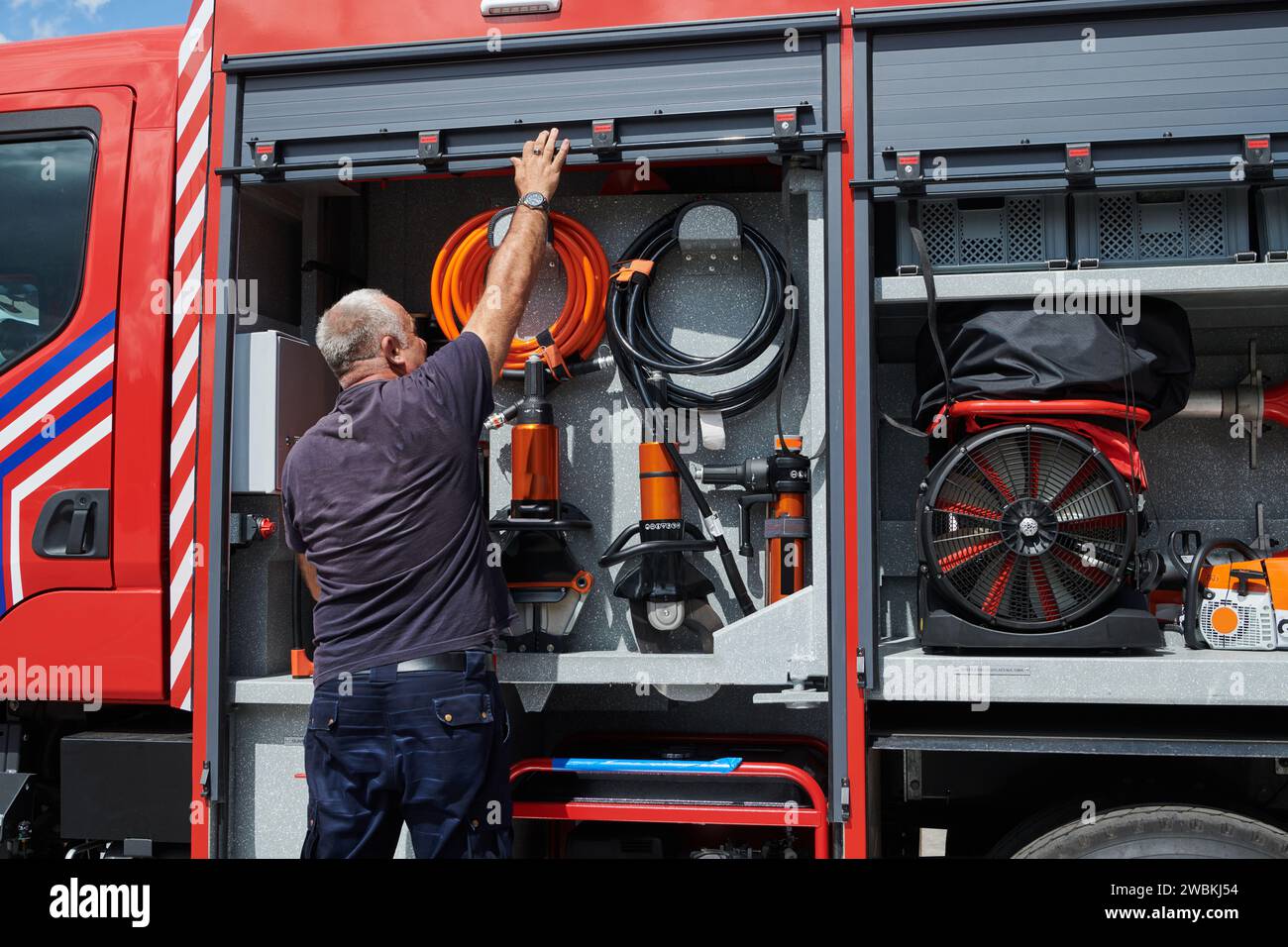 A dedicated firefighter preparing a modern firetruck for deployment to ...