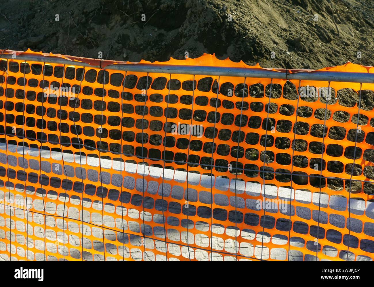 orange construction safety net in roadwork site with pile of soil in ...