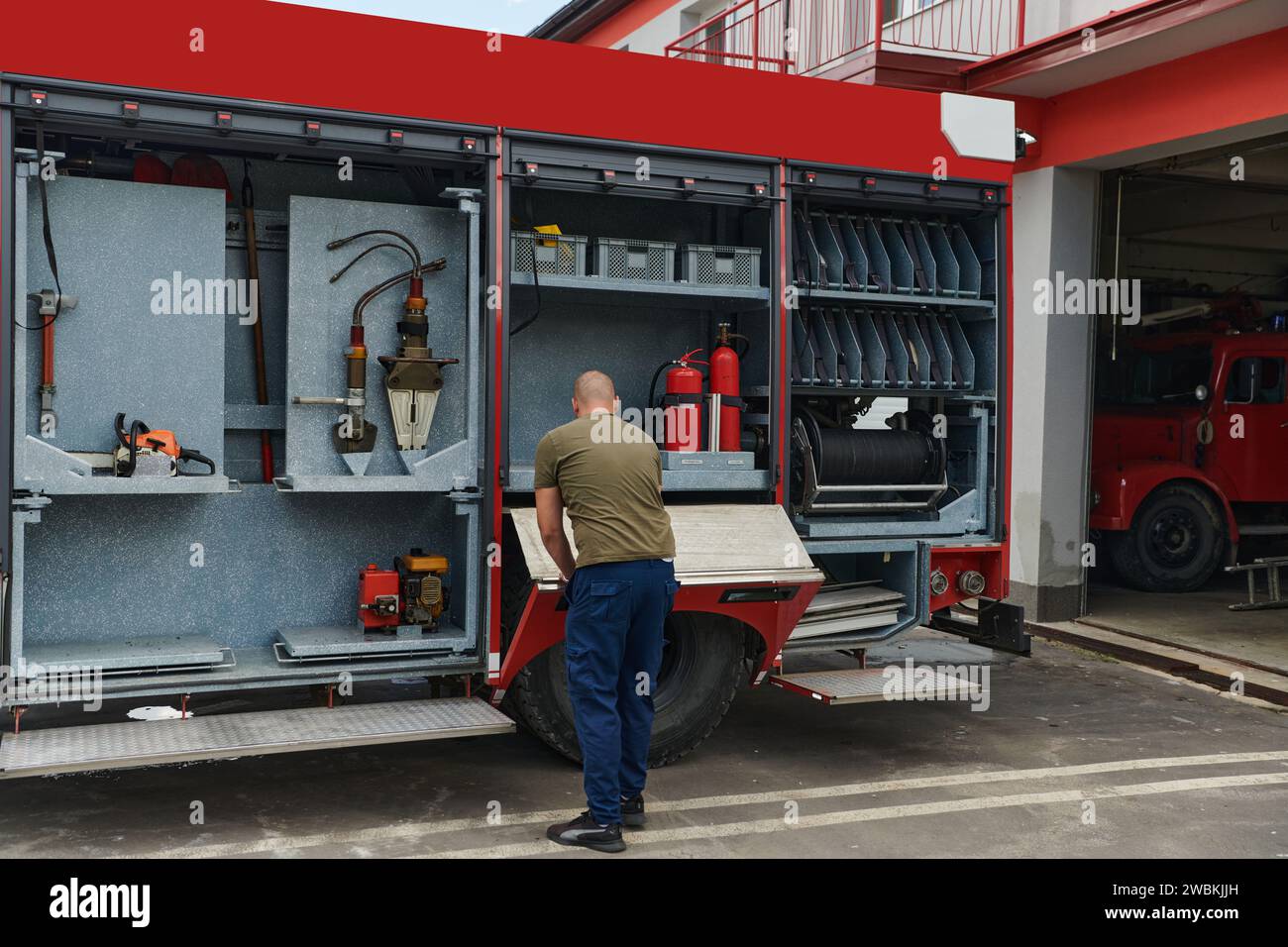 A dedicated firefighter preparing a modern firetruck for deployment to ...