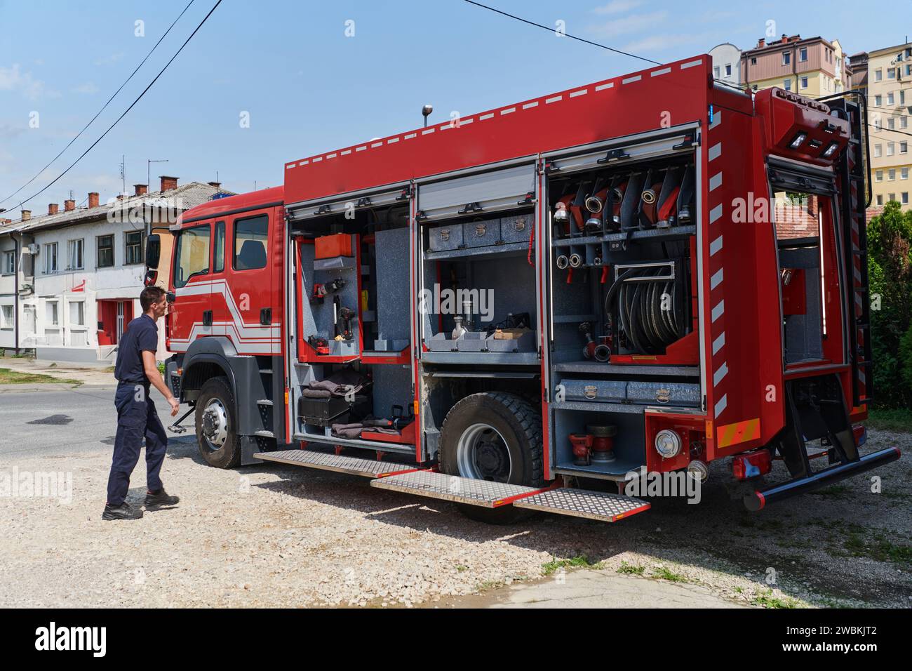 A dedicated firefighter preparing a modern firetruck for deployment to ...