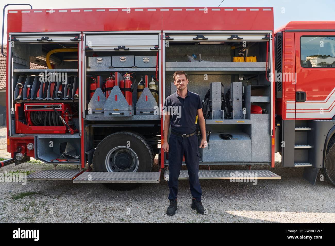 A confident firefighter strikes a pose in front of a modern firetruck ...