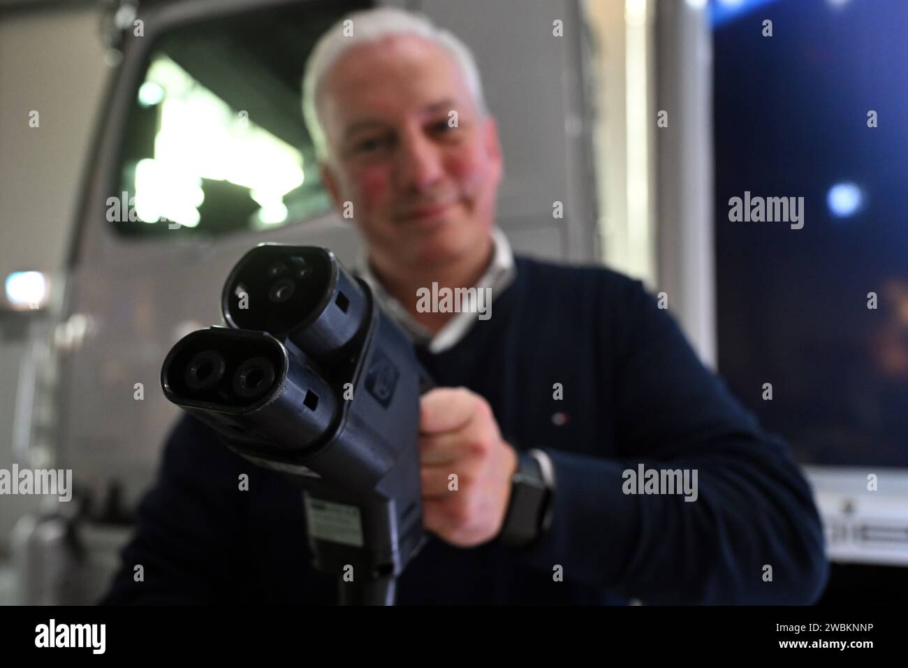 Essen, Germany. 11th Jan, 2024. An Eon employee holds a charging plug ...
