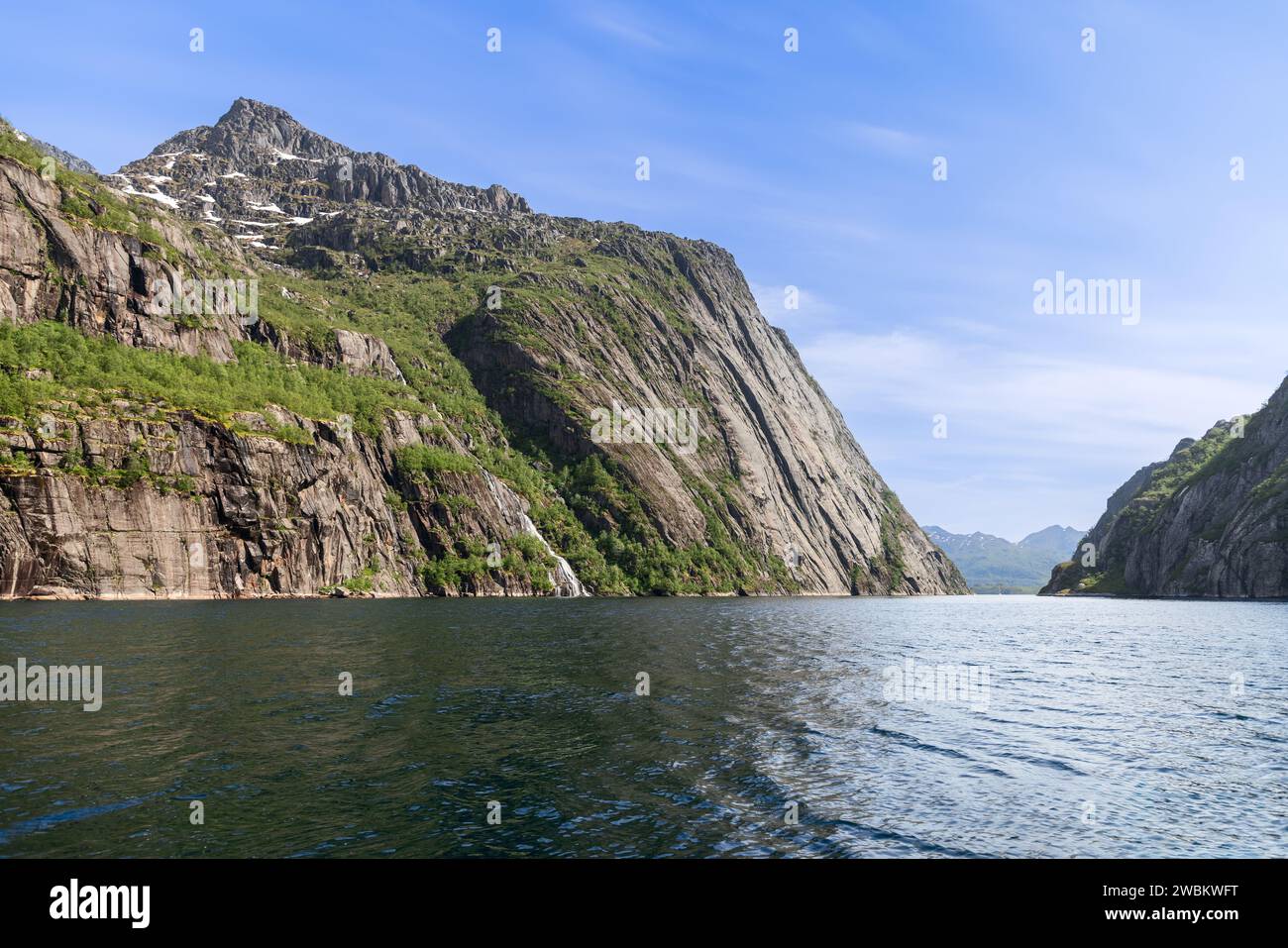 Steep rock faces and pockets of snow stand guard over the serene waters ...