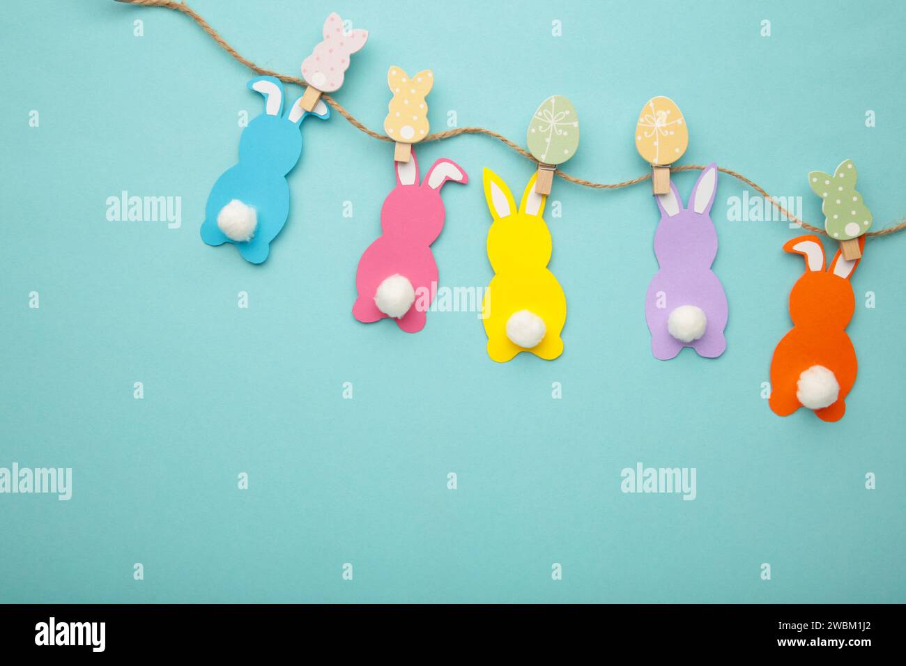 Easter rabbits handmade from colored paper on a rope with clothespins ...