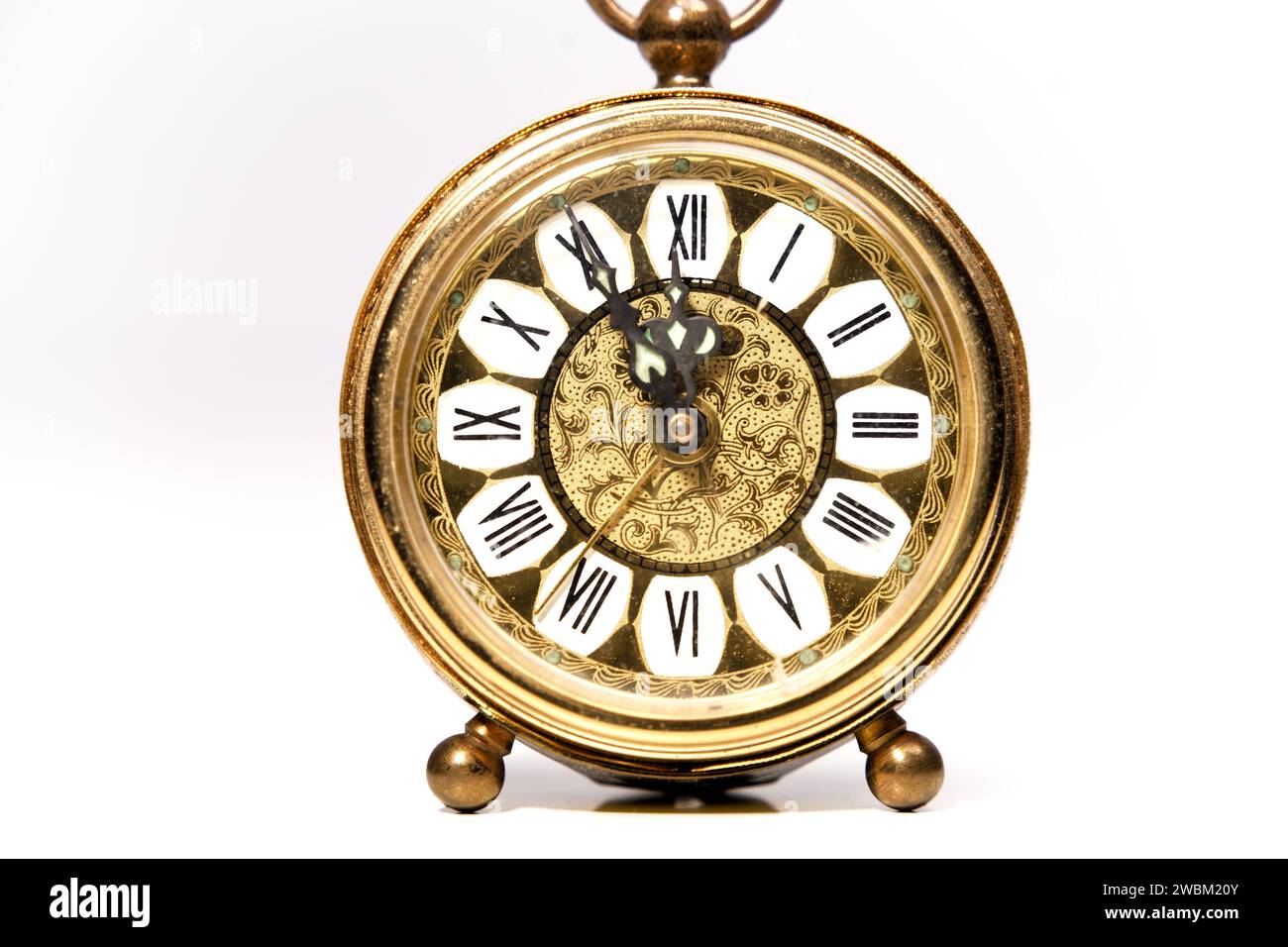 an old golden analog alarm clock with mechanical movement isolated on a ...