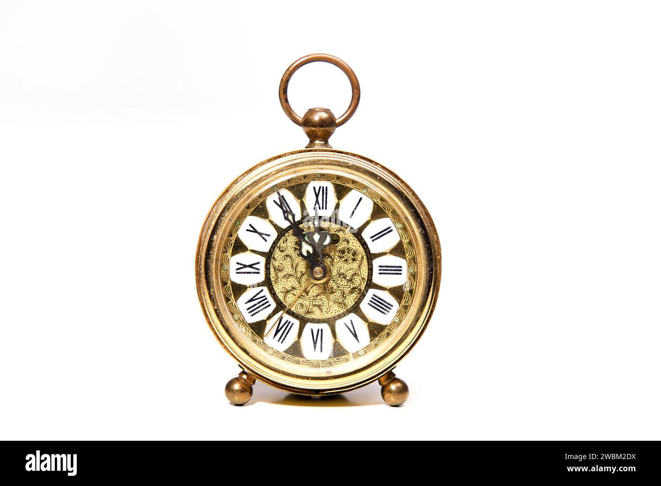 an old golden analog alarm clock with mechanical movement isolated on a ...