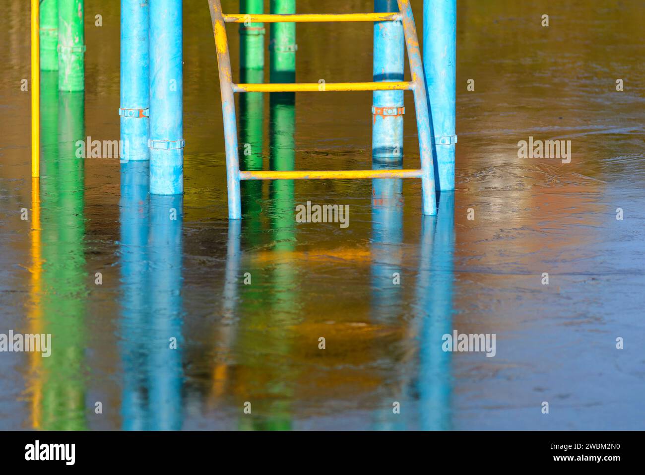 Colourful blue green yellow climbing frame and reflection in ice on ...
