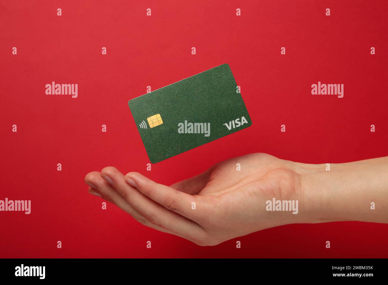 Hand with flying credit card Visa on red background. Top view Stock ...