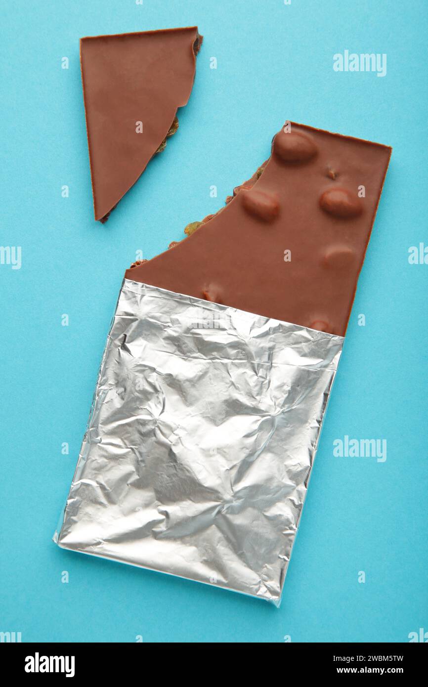 Bitten Chocolate bar in foil on blue background. With clipping path ...