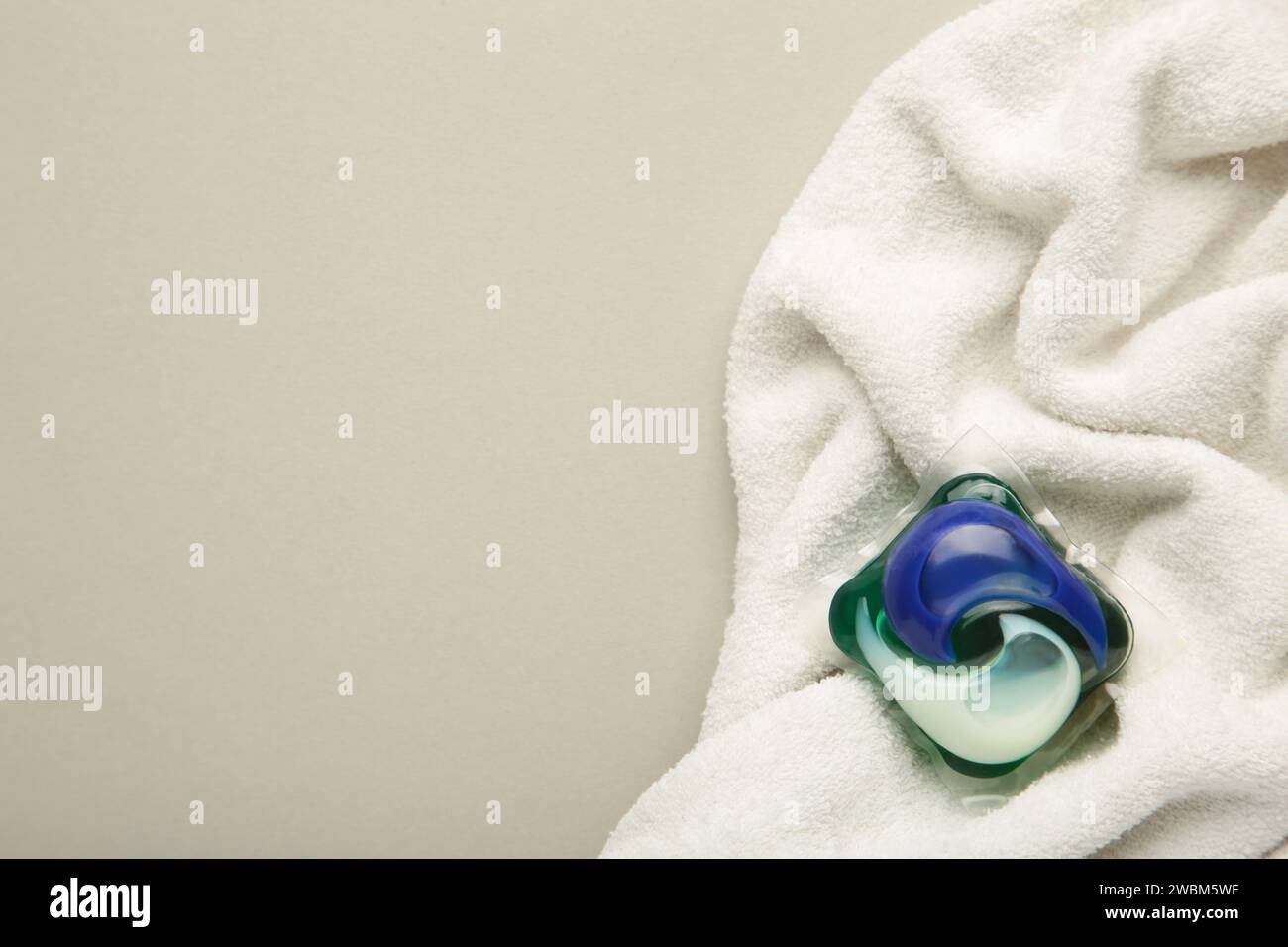 Laundry capsules. Laundry gel in capsules and white towel on grey ...