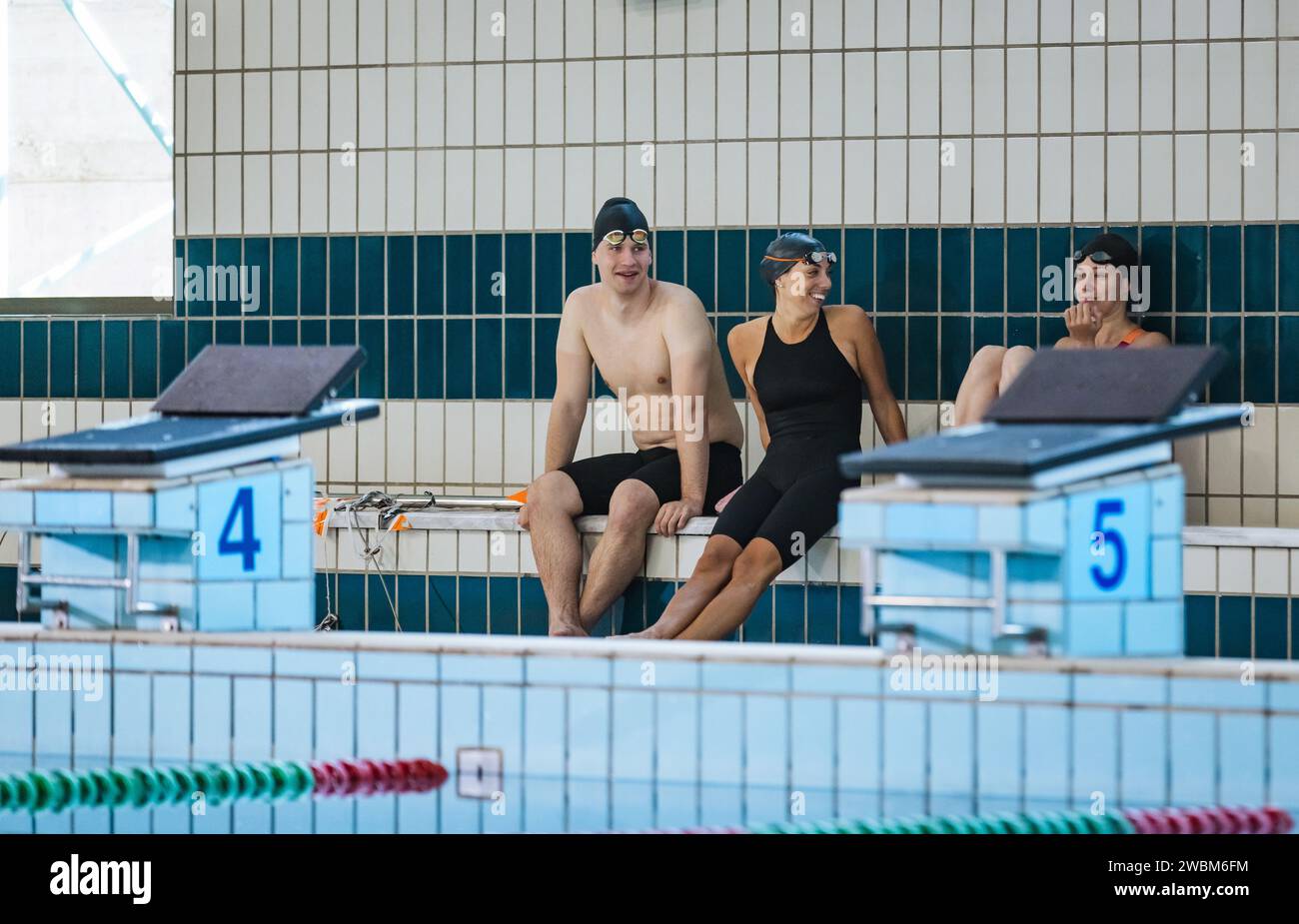 Young woman and men swimming club teammates sitting at the pool and ...