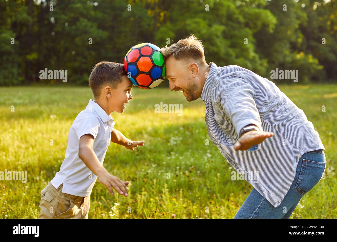Happy father and son are having fun and playing with ball in green park ...