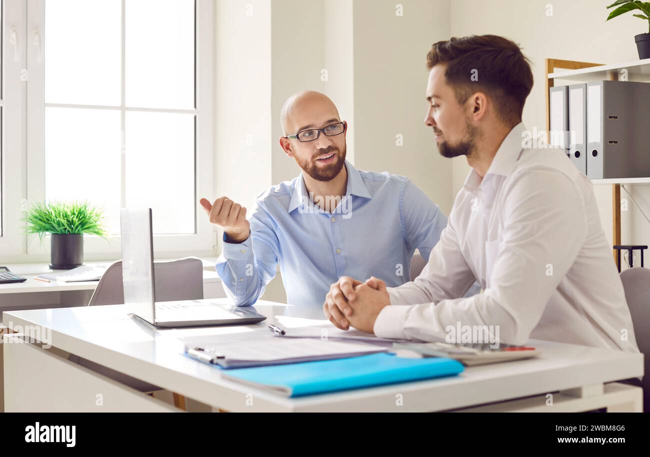 Two male business partners working with laptop together Stock Photo - Alamy
