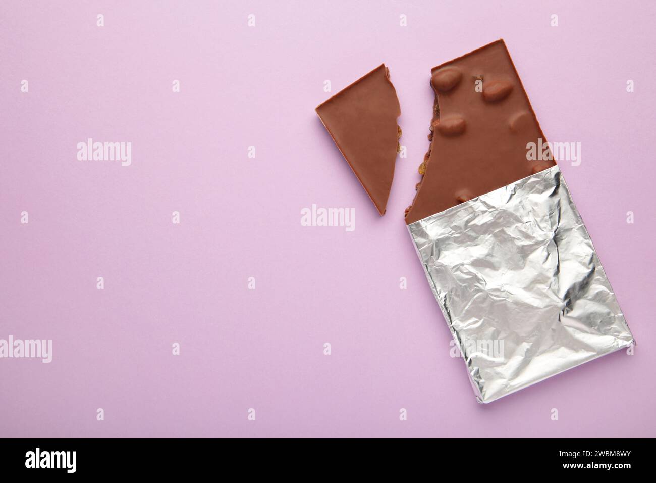Bitten Chocolate bar in foil on purple background. With clipping path ...